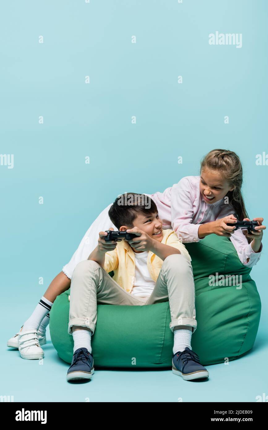 KYIV, UKRAINE - JULY 2, 2021: Smiling asian kid playing video game with ...