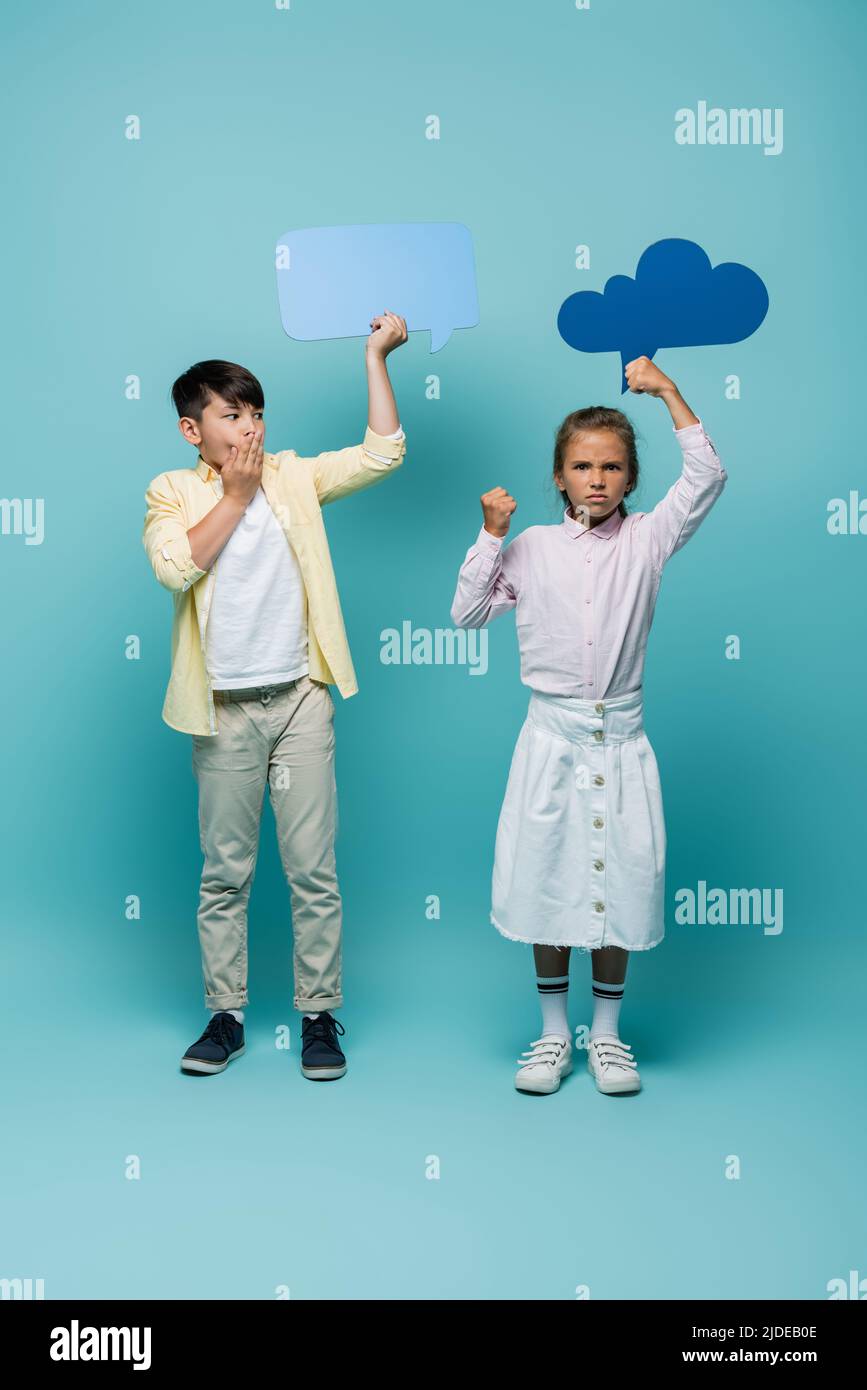 Aggressive schoolgirl holding thought bubble near scared asian friend ...