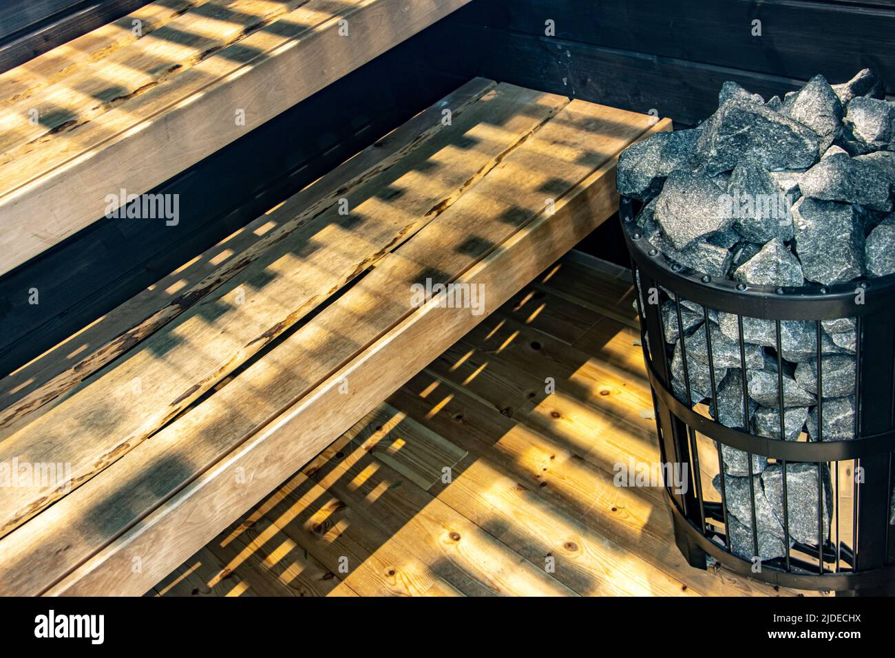 Interior of a Finnish sauna with benches and stones in an iron basket ...