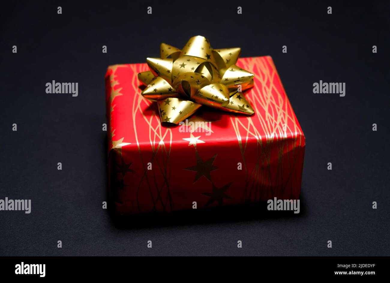 Red square gift box with a golden bow on a black background Stock Photo ...