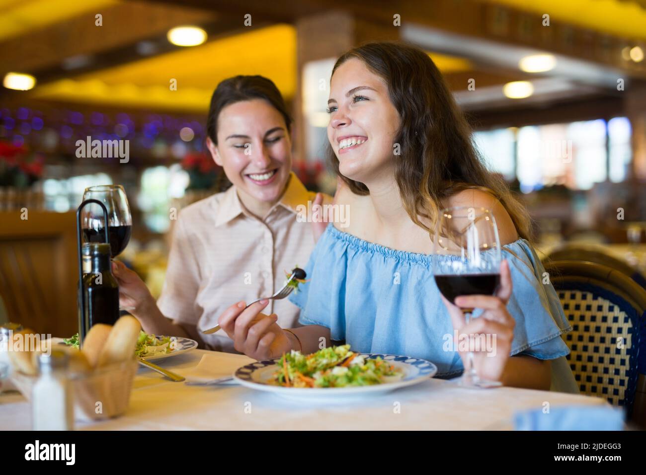 Two positive female best friends drinking wine in restaurant Stock ...