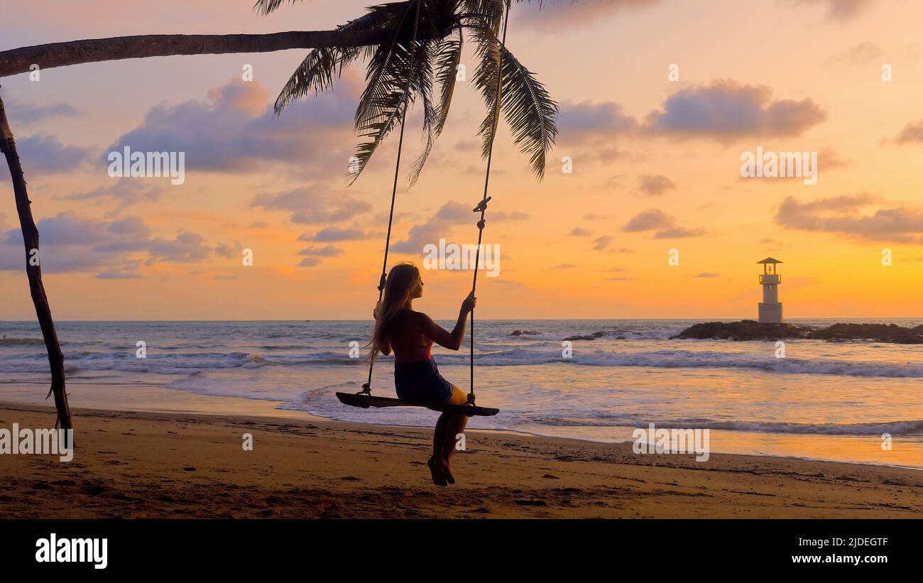 Silhouette of woman sitting on swing in sea at sunset hi-res stock ...