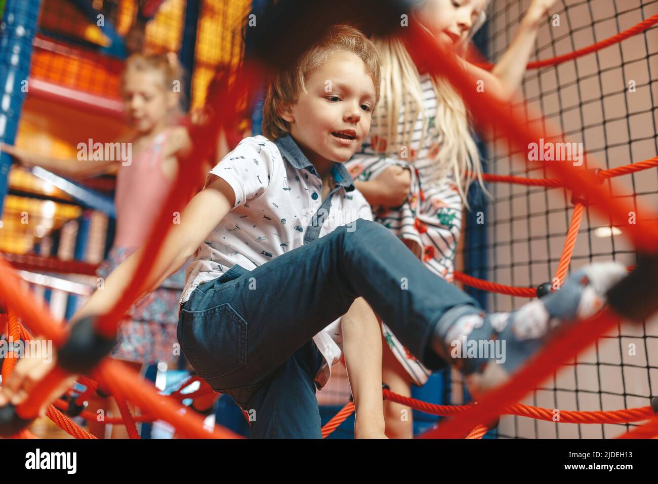Excited kids playing together on net ropes. Happy group of siblings ...