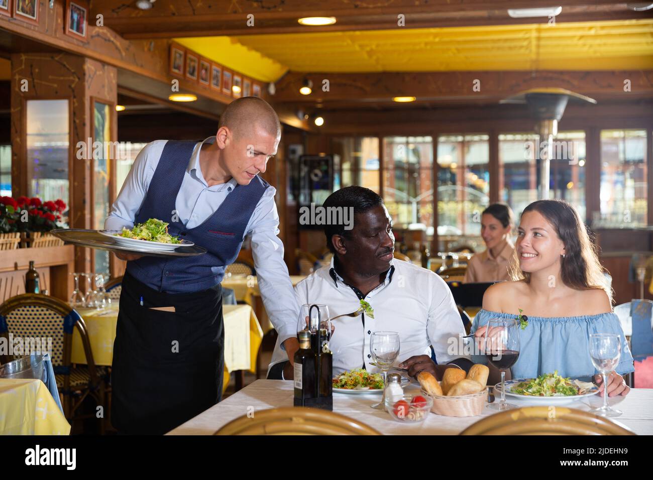 Waiter serving meals for couple at restaurant Stock Photo - Alamy