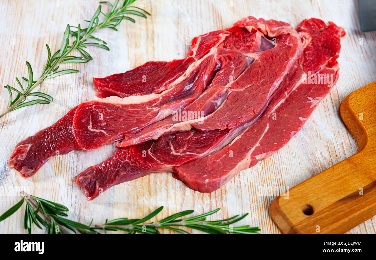 Unfinished beef steak with sprig of rosemary on cutting board Stock ...
