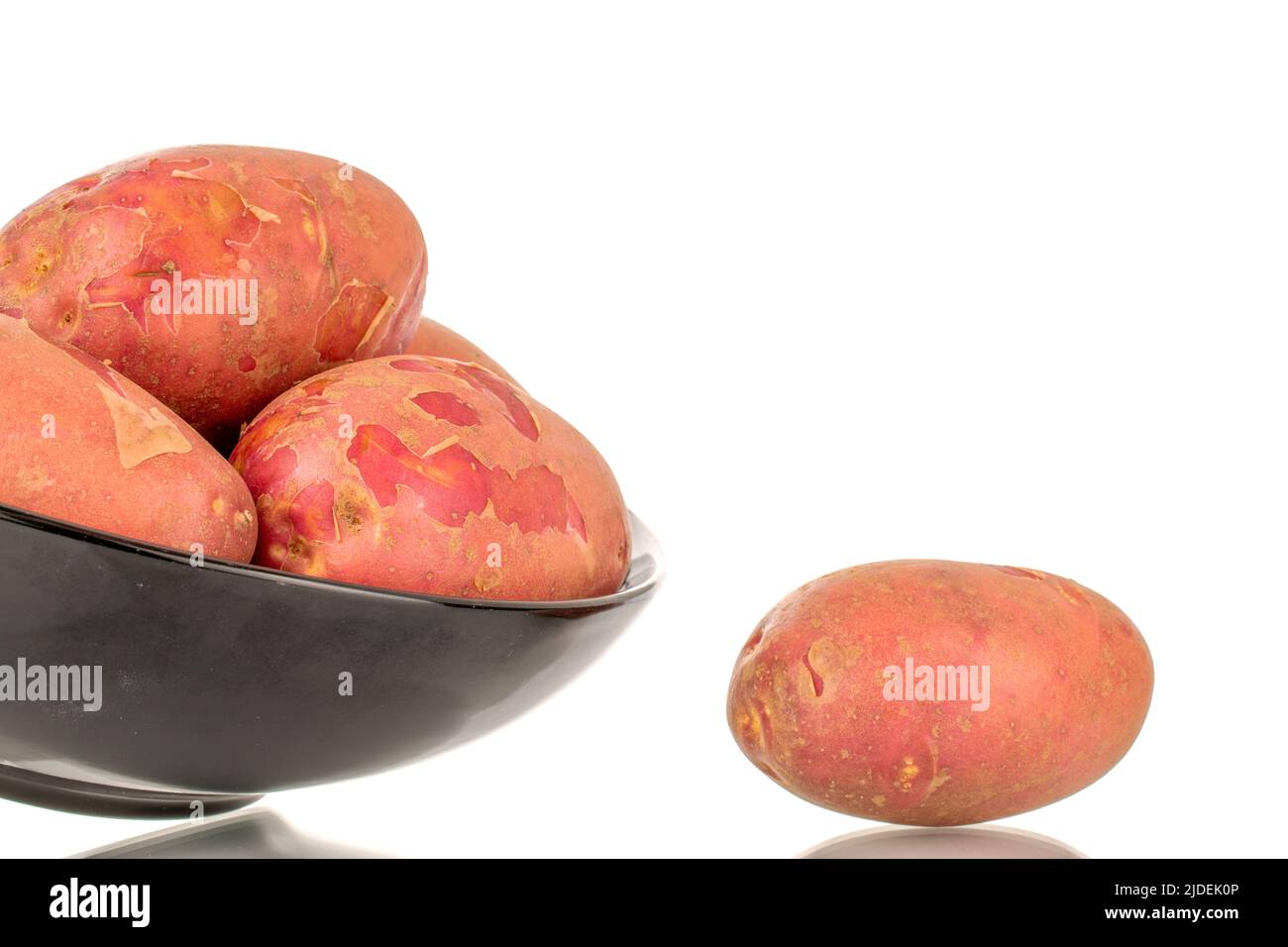 Several organic pink potatoes on a ceramic black dish, close-up ...