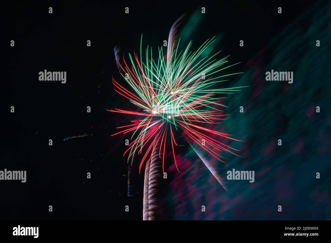 Bright festive salute of red-green color, with haze, in the night sky ...