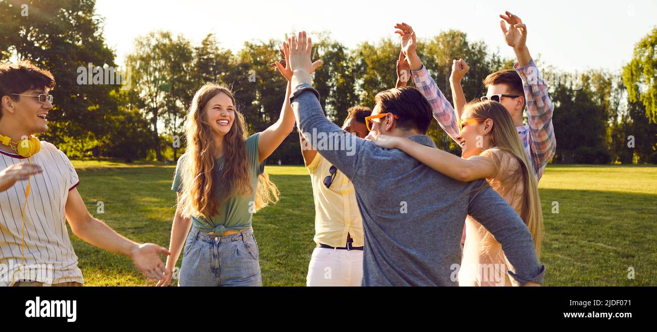 Group of happy cheerful young friends meeting in park and having fun ...