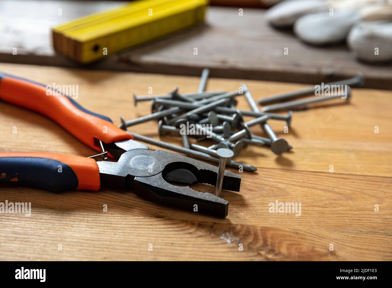 Pliers and nail stack on wood. Carpenter work bench table, closeup view ...