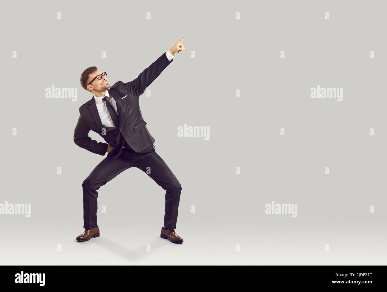 Happy funny excited businessman pointing at something on gray copy ...