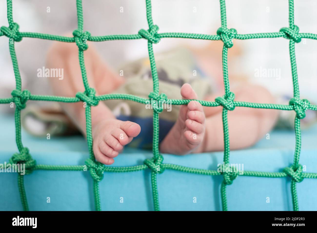 Close-up detail macro view of cute baby leg foot fingers in crib with ...