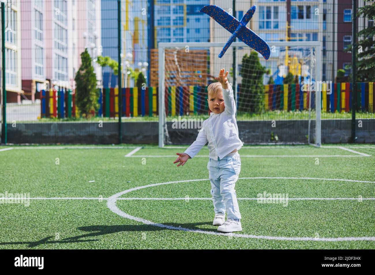 A child runs in the park with a toy airplane. A boy in a white shirt ...