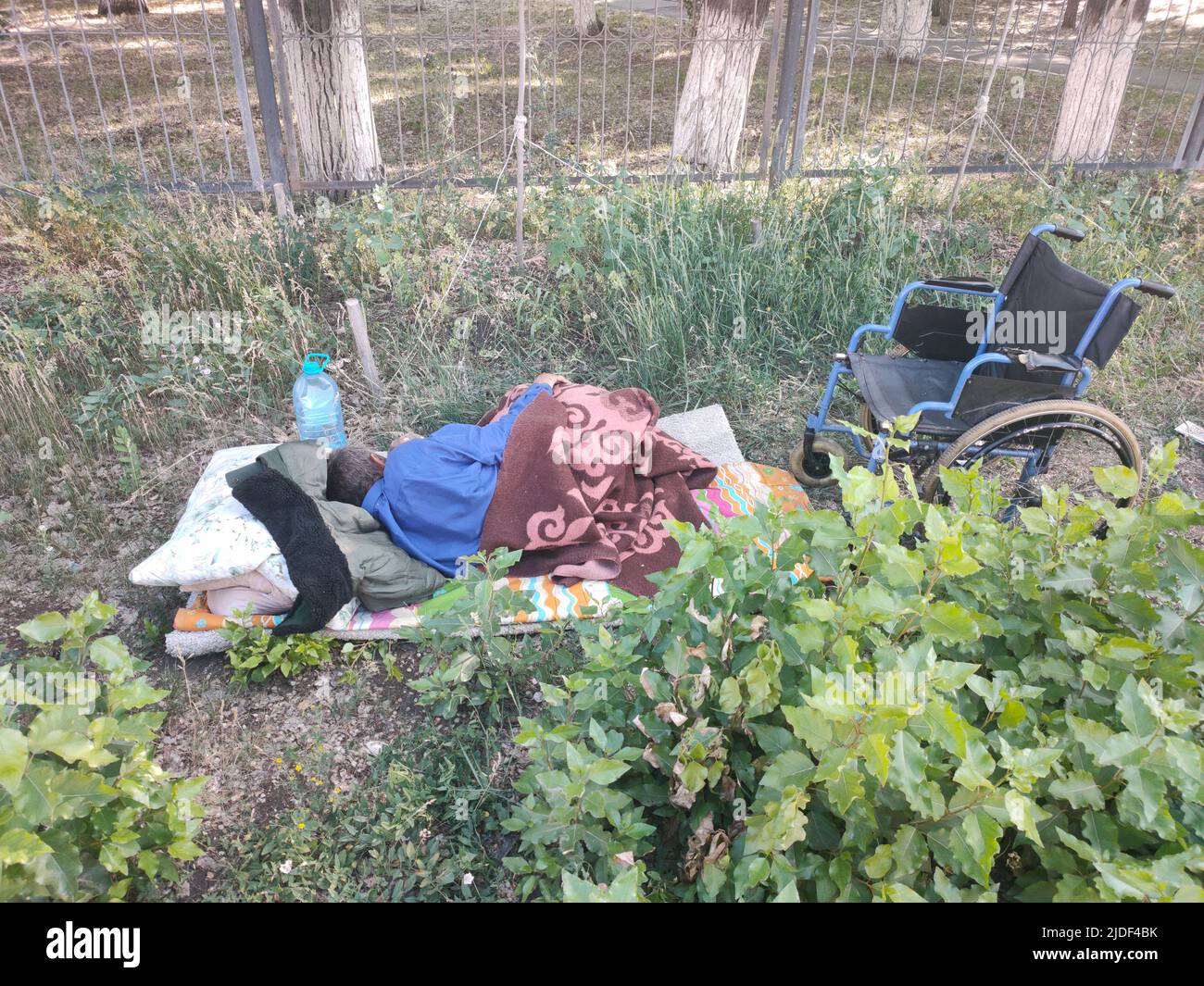 Homeless man laying sleeping on the street with wheelchair background ...