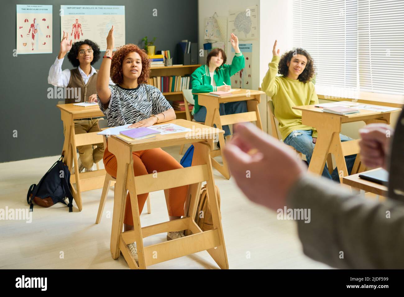 Group of clever intercultural teenage students of high school raising ...