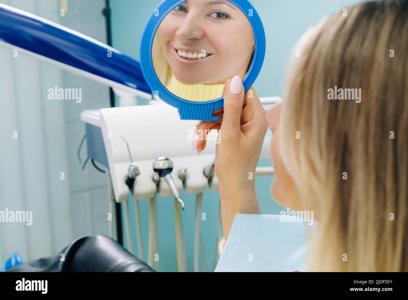 The girl smiles and looks in the mirror in dentistry Stock Photo - Alamy