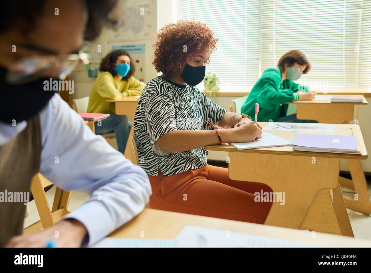 Female highschool student writing down notes in copybook among ...