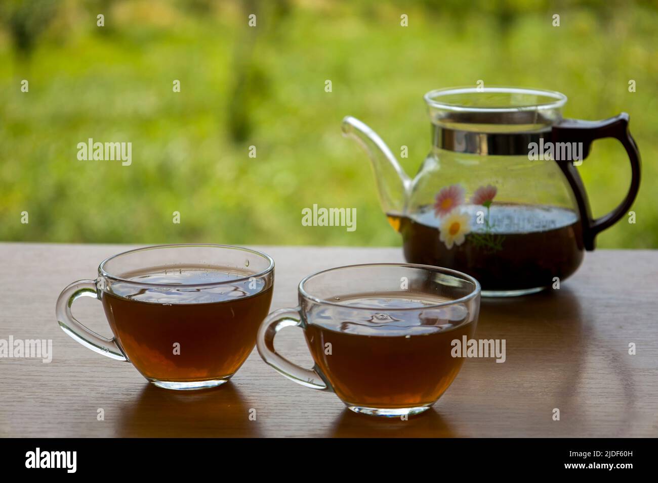 Teapot with a transparent cup of tea in nature Stock Photo - Alamy