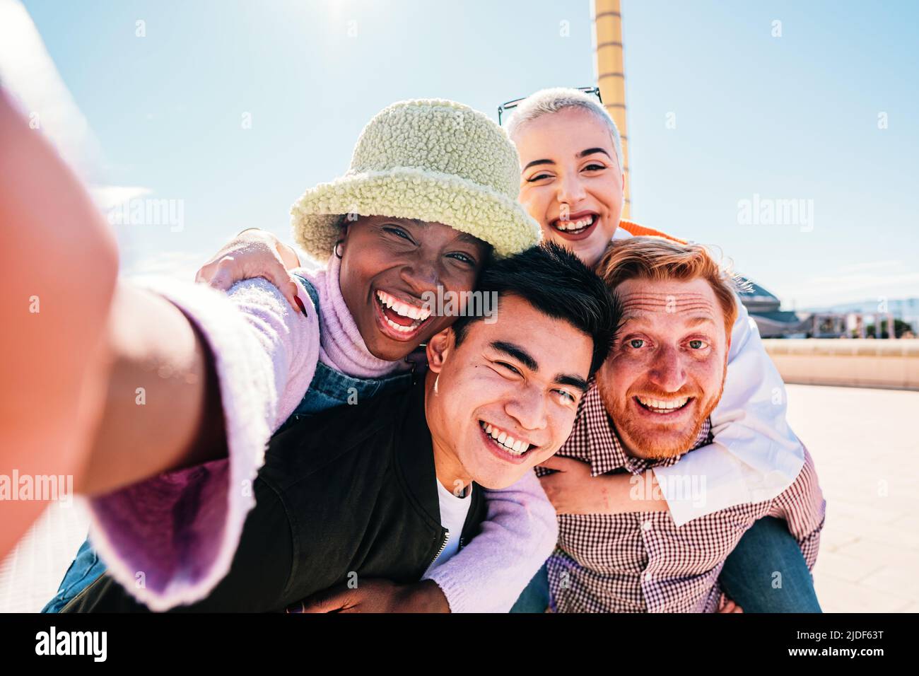 Group of friends giving piggyback ride to girlfriends. Happy young ...