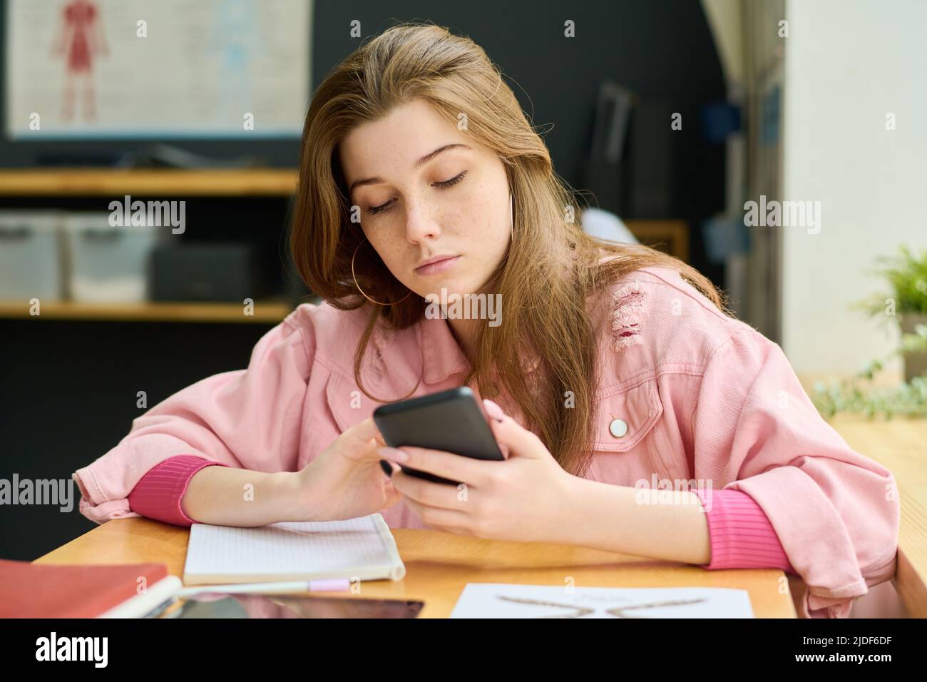 Teenage female student looking at smartphone screen while searching ...
