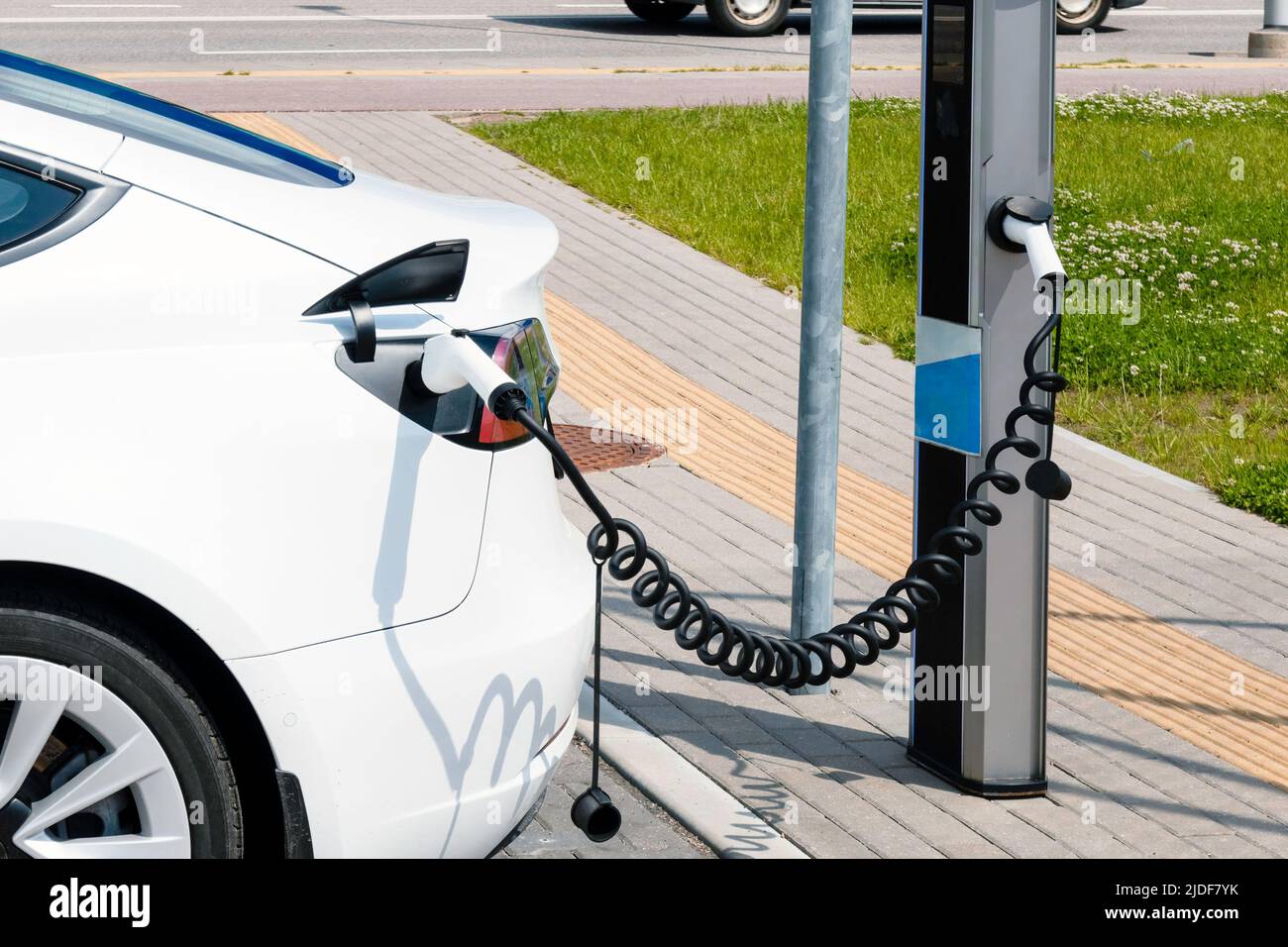 Close up of power supply plugged into gray electric car being charged ...