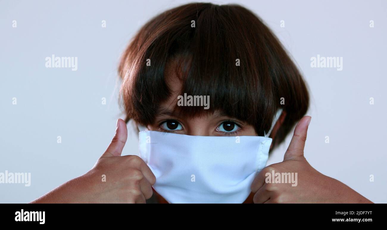 Child putting on covid-19 mask against pandemic prevention. Mixed race ...