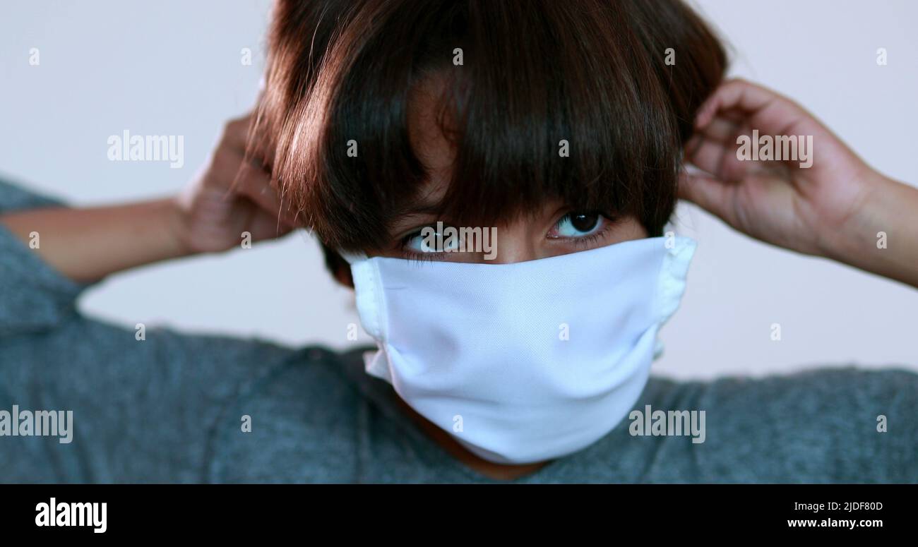 Child putting on covid-19 mask against pandemic prevention. Mixed race ...