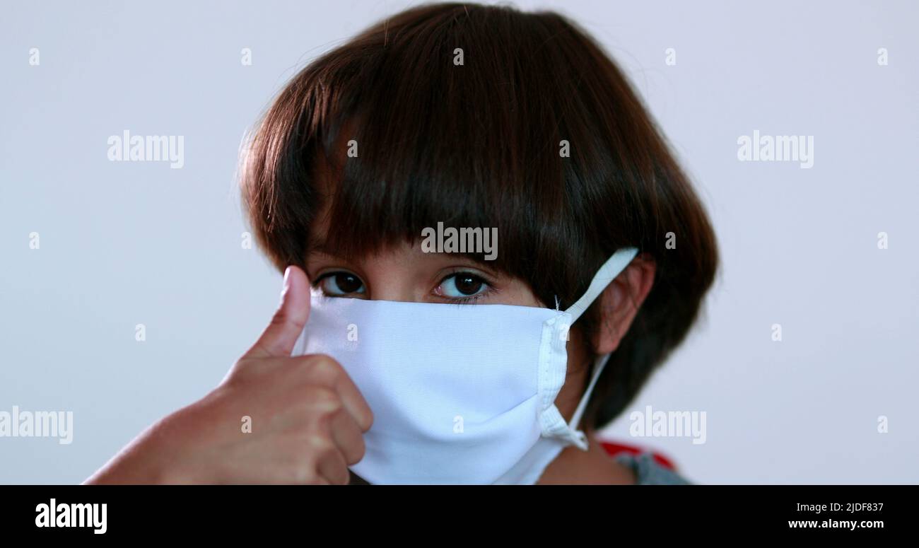 Child wearing surgical mask giving thumbs up, kid portrait wearing ...
