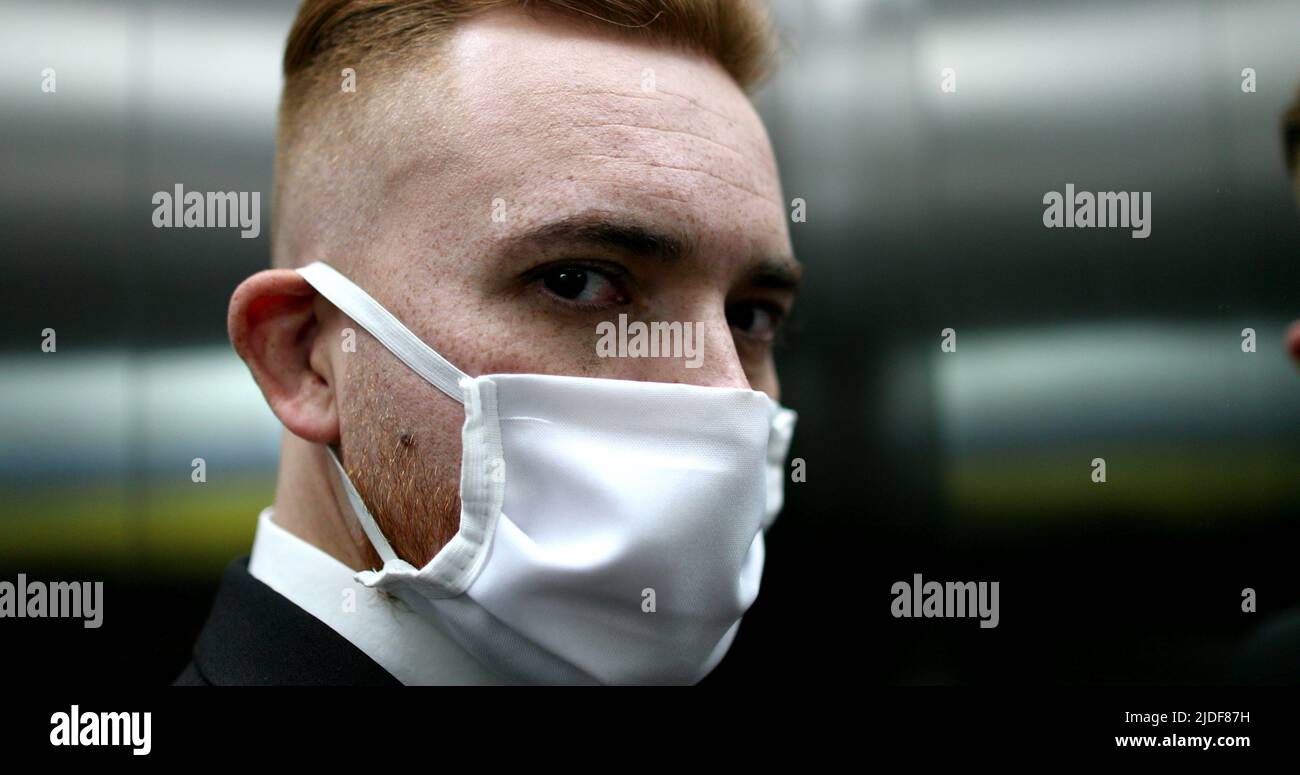 Man putting on face mask inside elevator mirror, person wearing covid ...