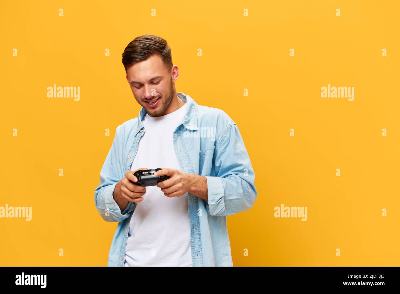 Overjoyed tanned handsome gamer man in blue basic t-shirt hold joystick ...