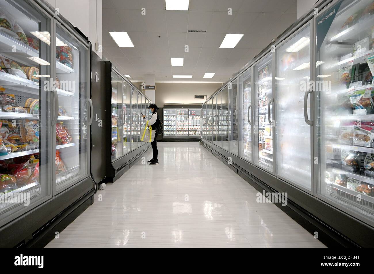 A woman looks at her phone as she shops in the frozen aisle of a Target ...