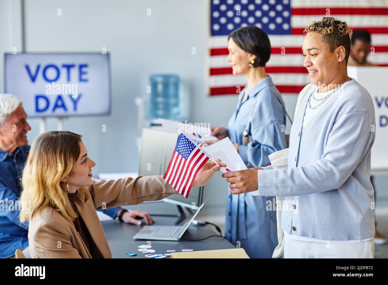 Side view portrait of smiling black woman taking ballot at voting ...