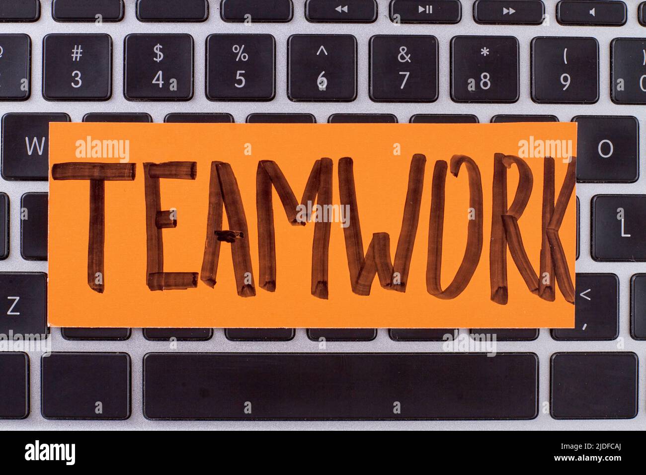 Paper with teamwork word on laptop keyboard. Word written by marker pen ...