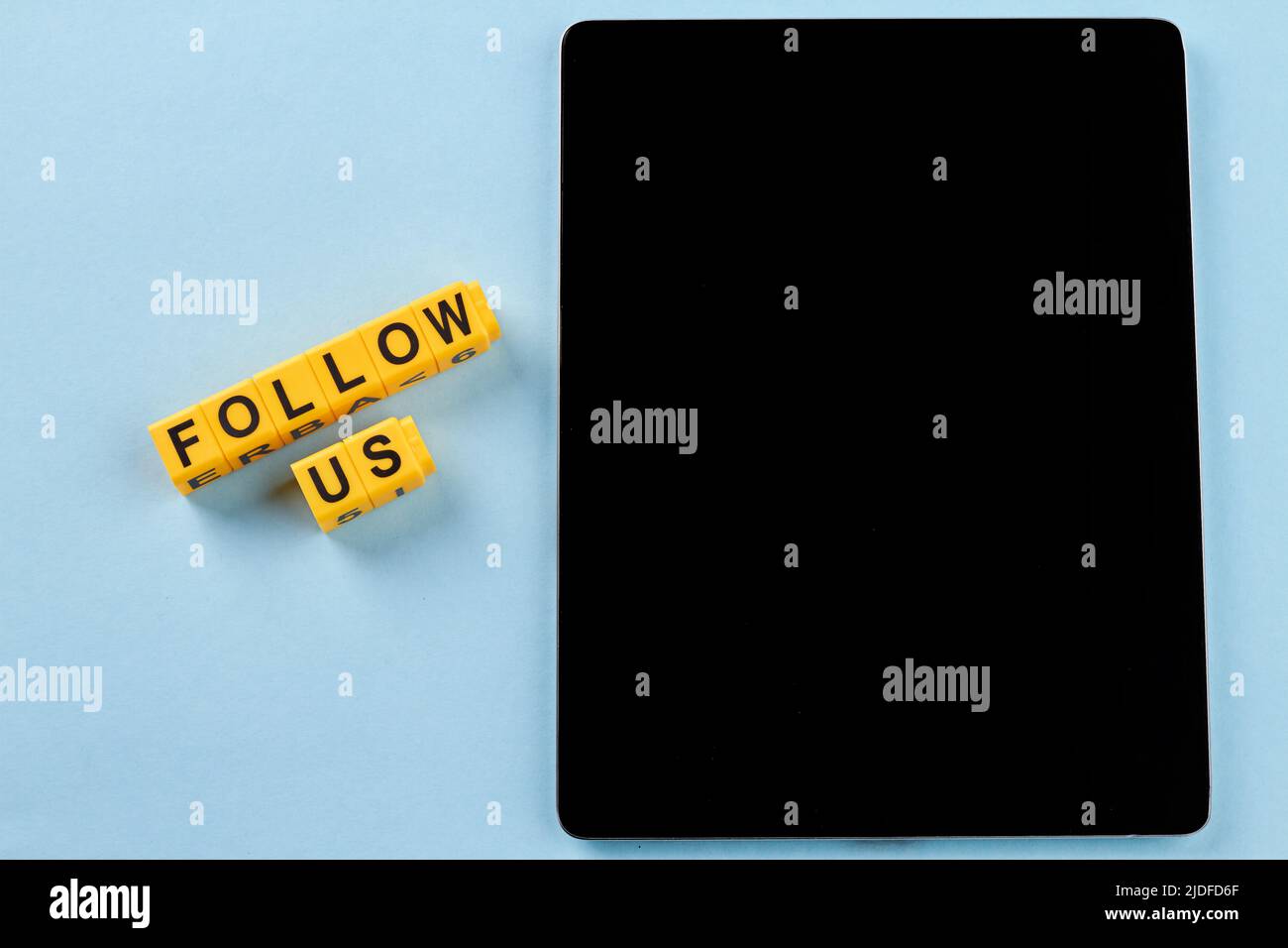 Tablet pc with black screen on blue background. Yellow cube letters ...