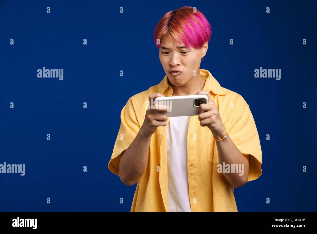 Asian boy with pink hair playing online game on mobile phone isolated ...
