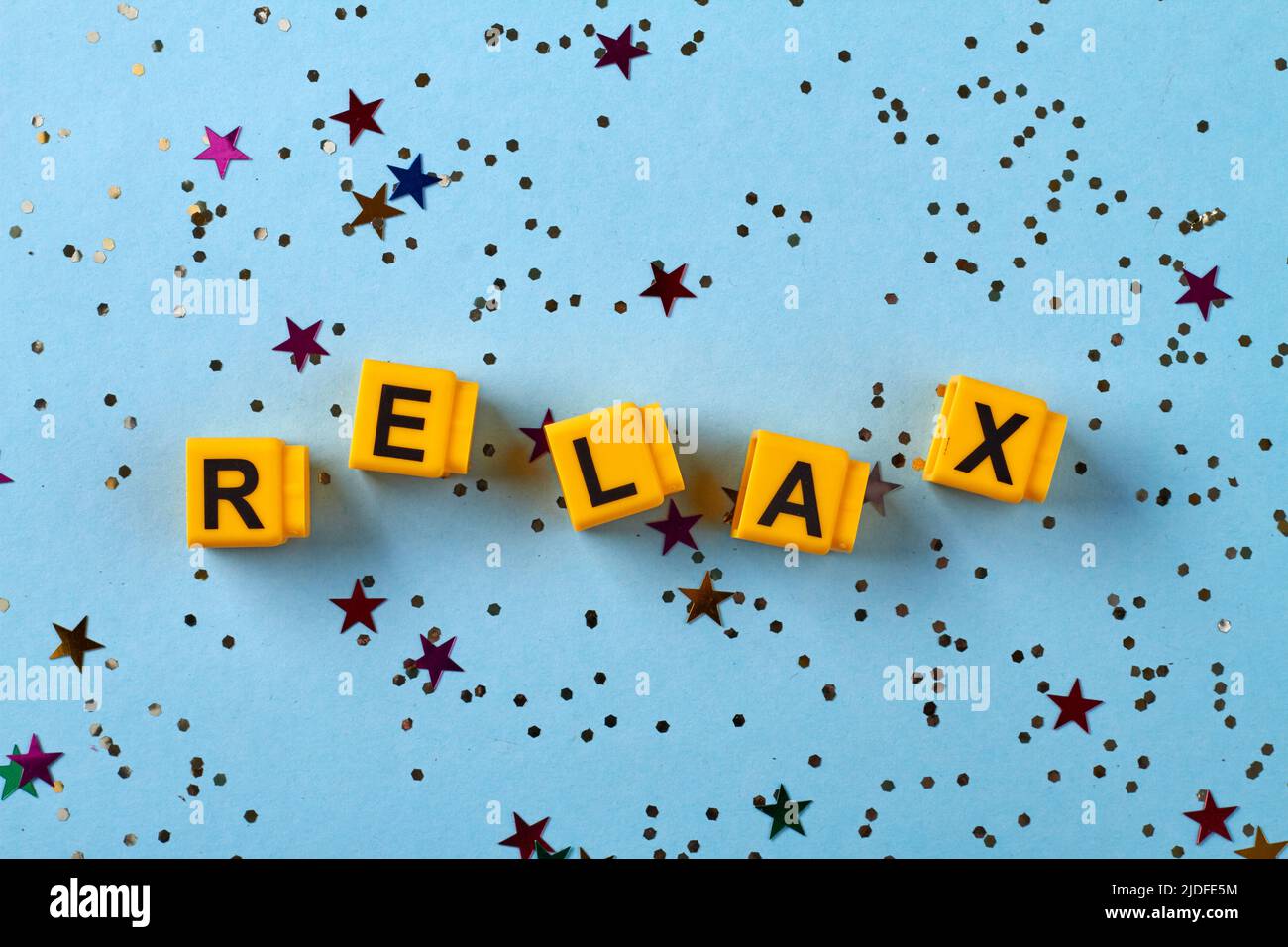Flat lay yellow letter cubes arranged in relax word. Sequins confetti ...