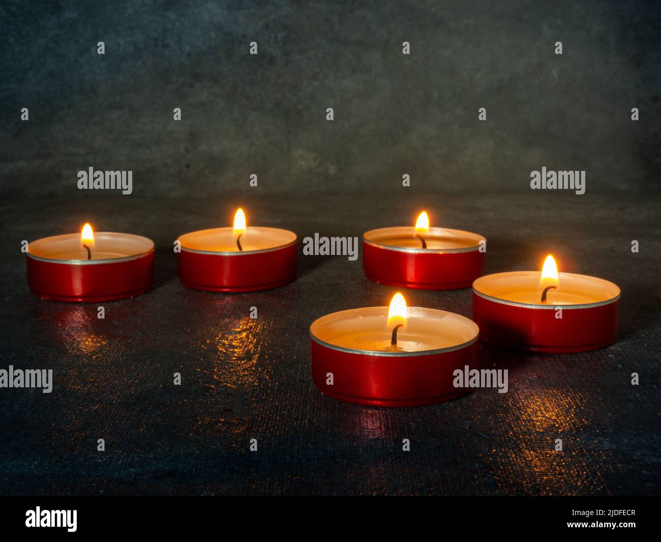 Small candles burn orange in the dark. Mysterious setting. Waiting for ...
