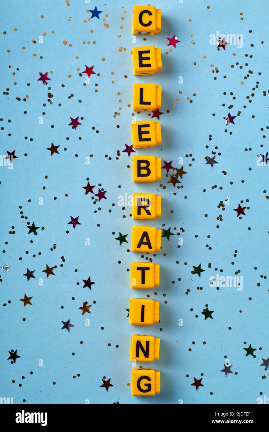 Vertical shot of celebrating word made of yellow letter cubes. Confetti ...
