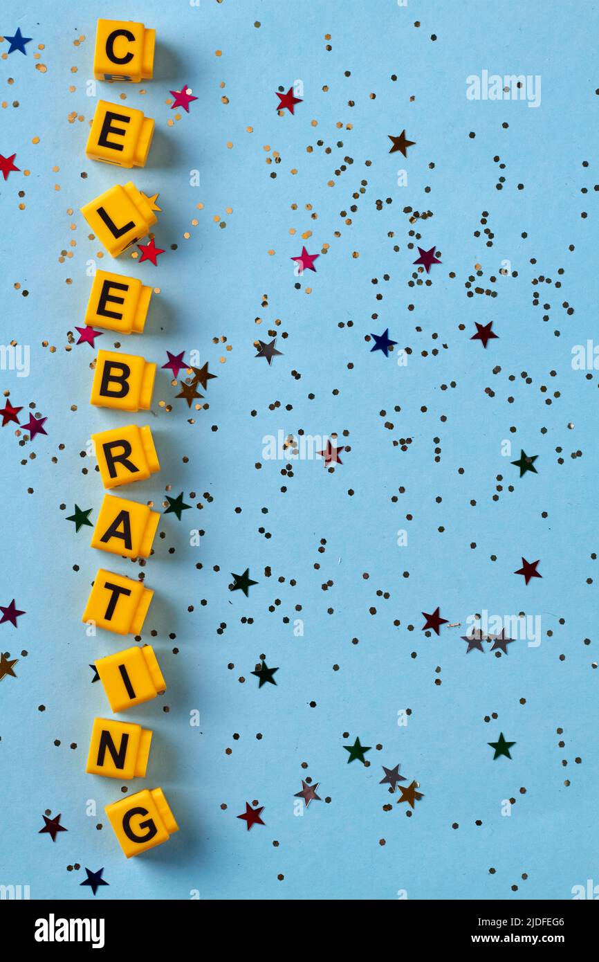 Vertical shot of celebrating word on blue background with confetti. Top ...