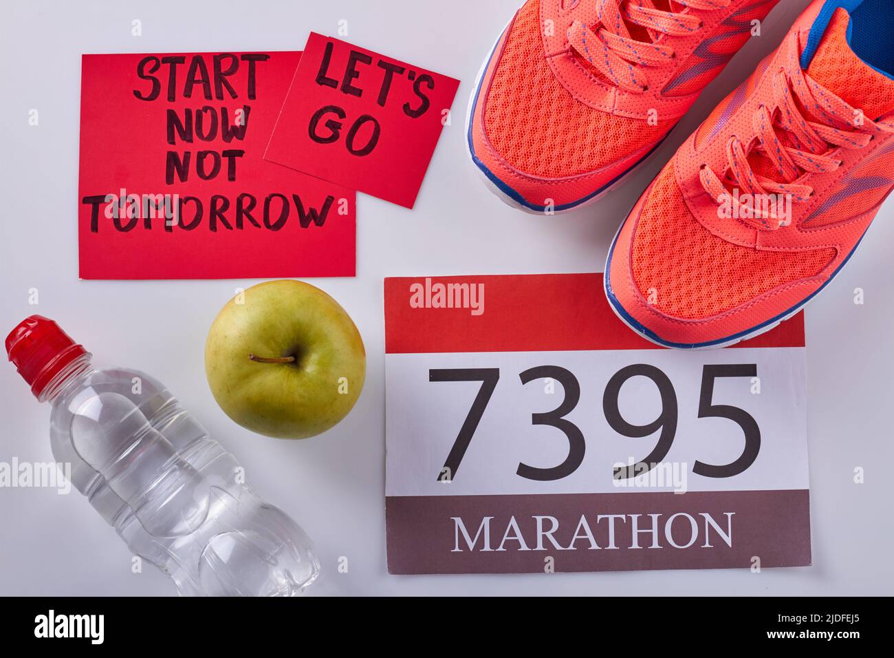 Flat lay marathon accessories on white background. Red shoes with green ...