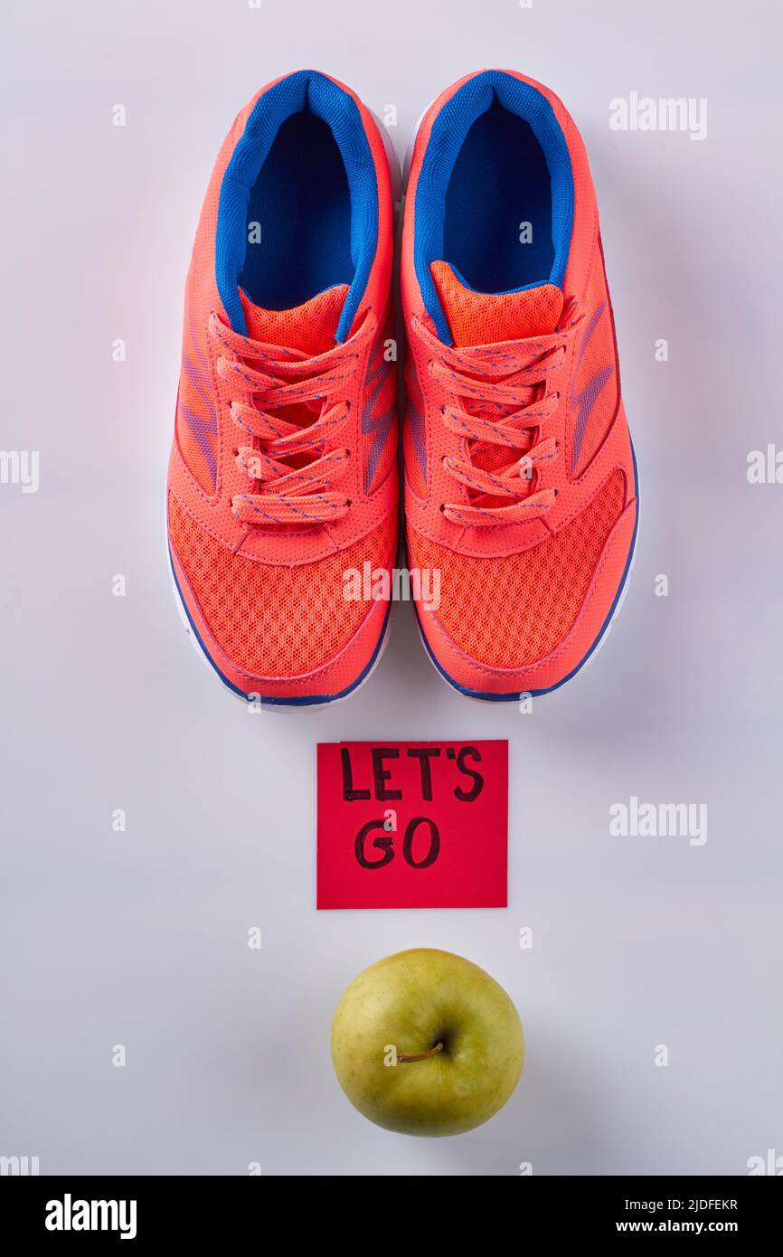 Vertical shot red sneakers and green apple. Lets go inscription on ...
