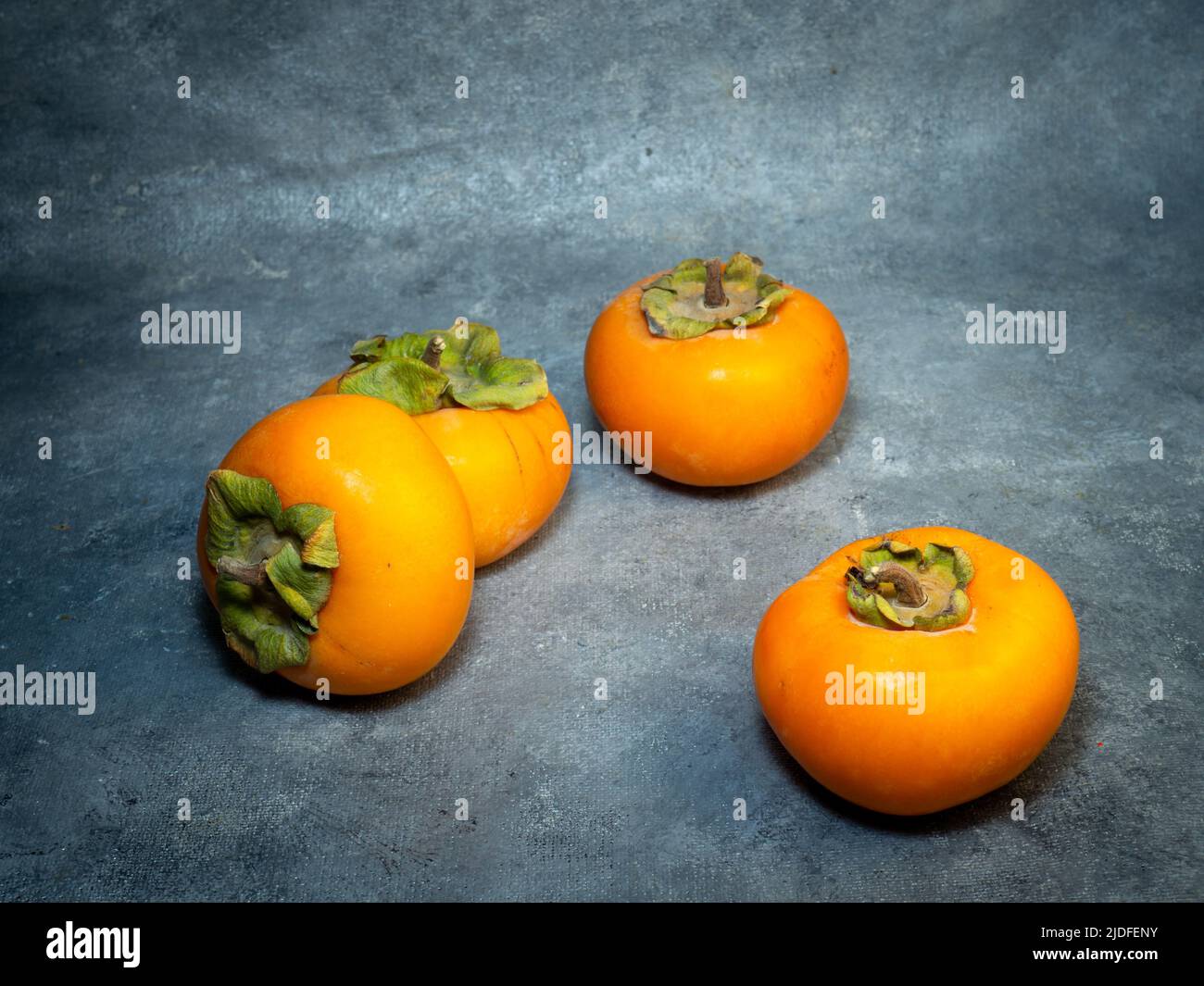 Four persimmons on a black background. Persimmon varieties Chamomile ...