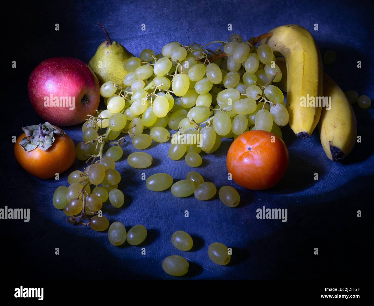 Still life of fruits. apple, persimmon, pear and grapes on a black ...