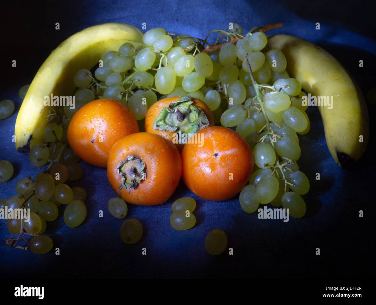 Still life of fruits. apple, persimmon and grapes on a black background ...