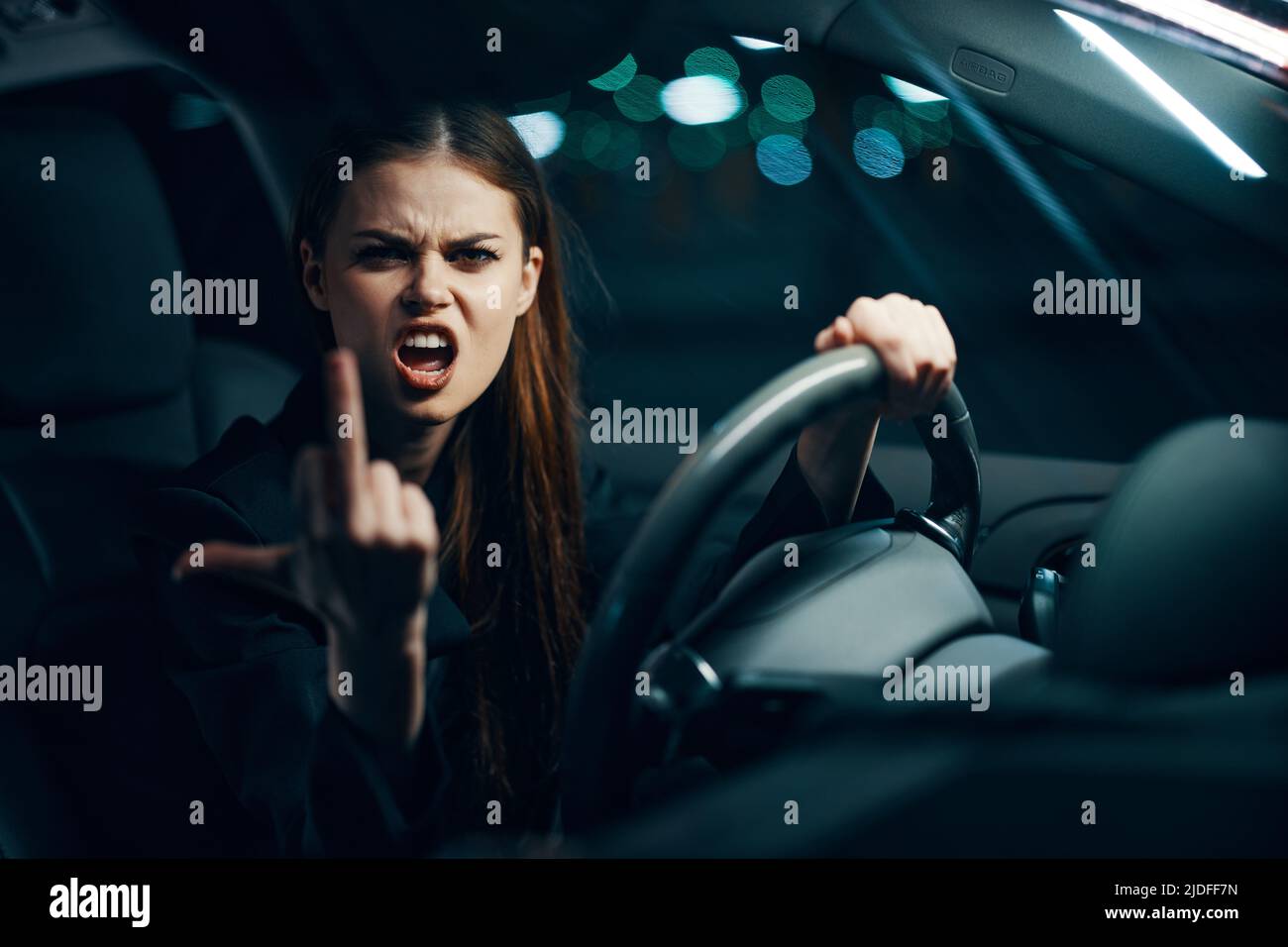 an angry, aggressive woman sits behind the wheel of a car wearing a ...