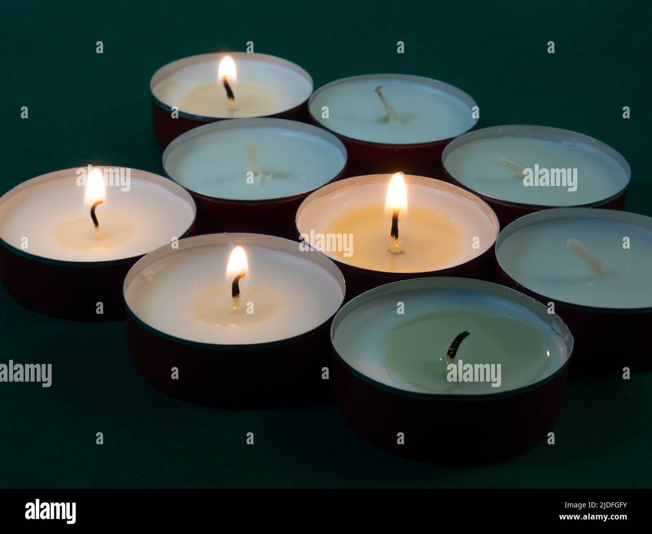 Short candles are burning against a dark background. Lots of small ...