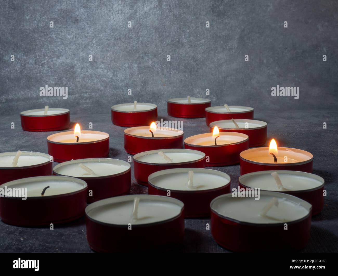 Short candles are burning against a dark background. Lots of small ...