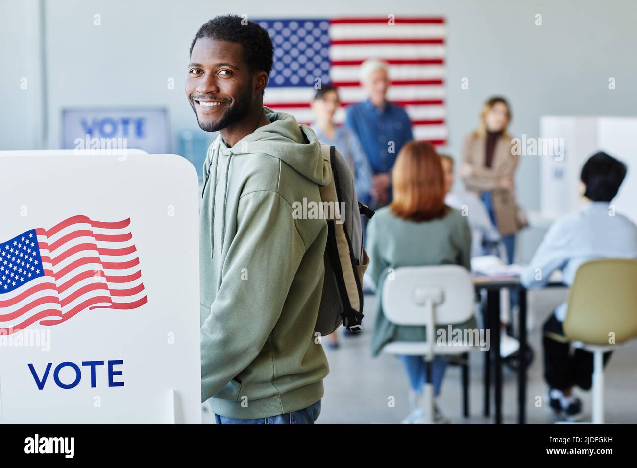 Side view portrait of smiling black man voting in booth on election day ...