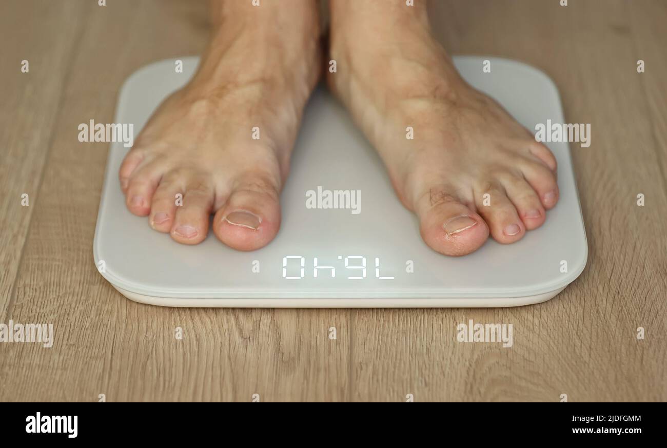 Man weighing himself - male bare feet stepping on white digital floor ...