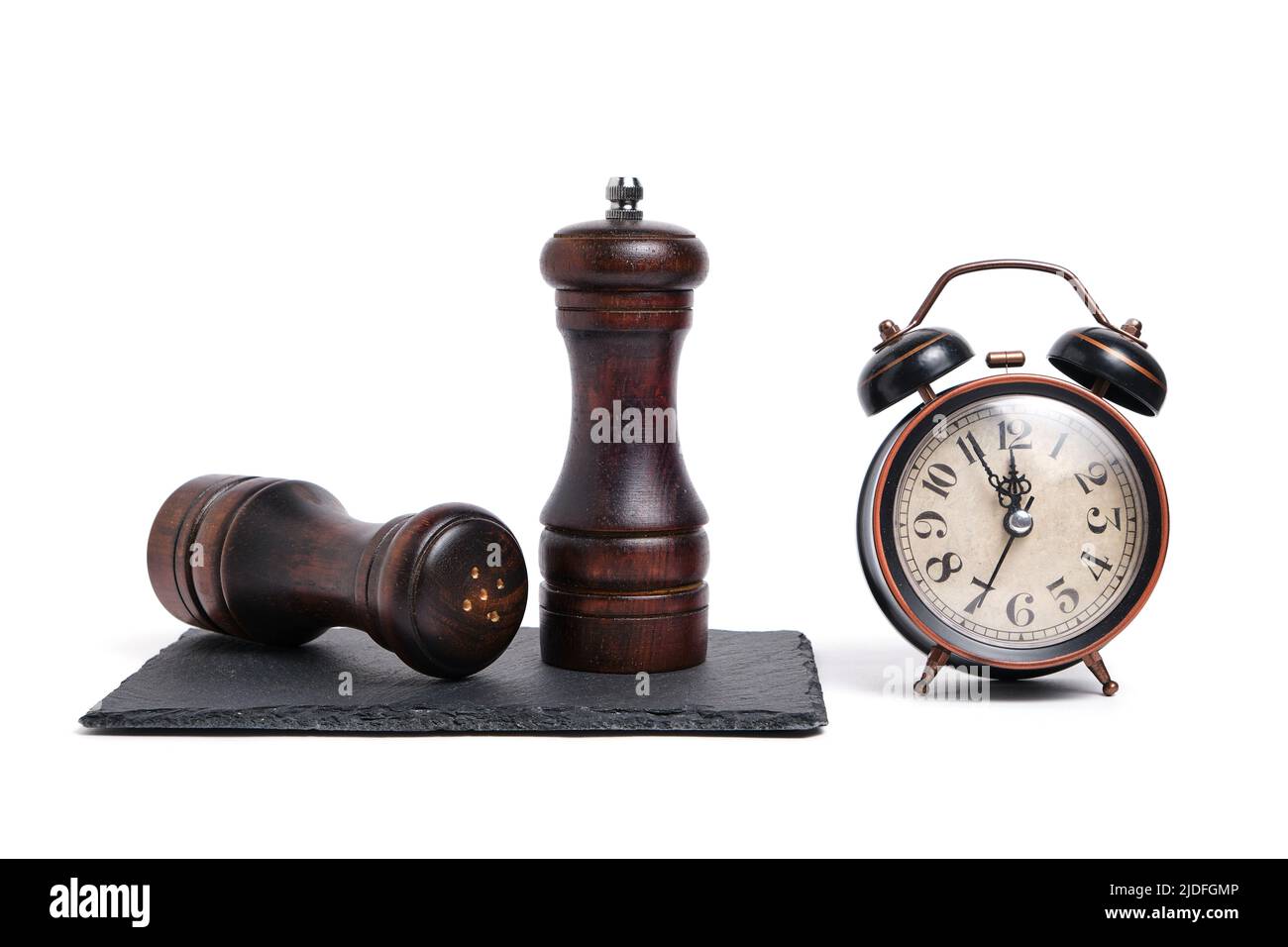 Alarm clock, wooden pepper shaker and salt shaker on a slate stone on a ...