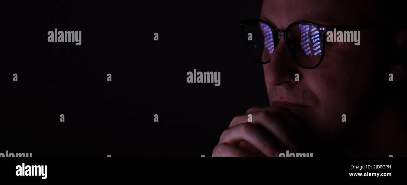 male working online late. Close up side view of focused man wears ...